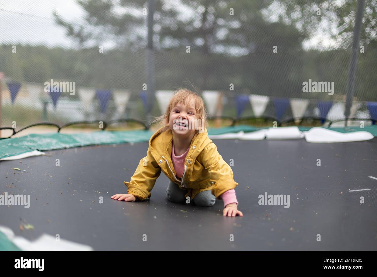 Little girl jumping on trampoline and going down the slide Stock Photo ...