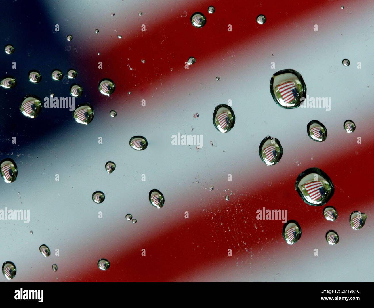 An American flag is refracted in raindrops on a window at a Fourth of ...