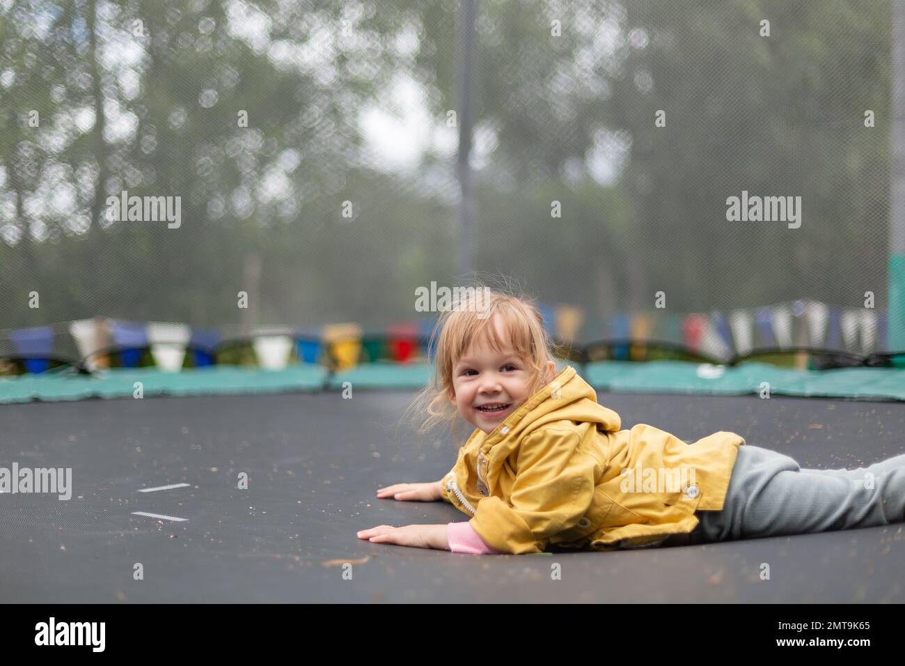 Little girl jumping on trampoline and going down the slide Stock Photo ...