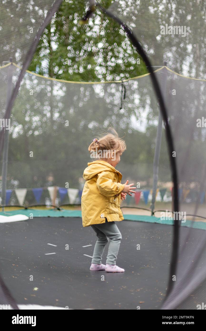Little girl jumping on trampoline and going down the slide Stock Photo ...