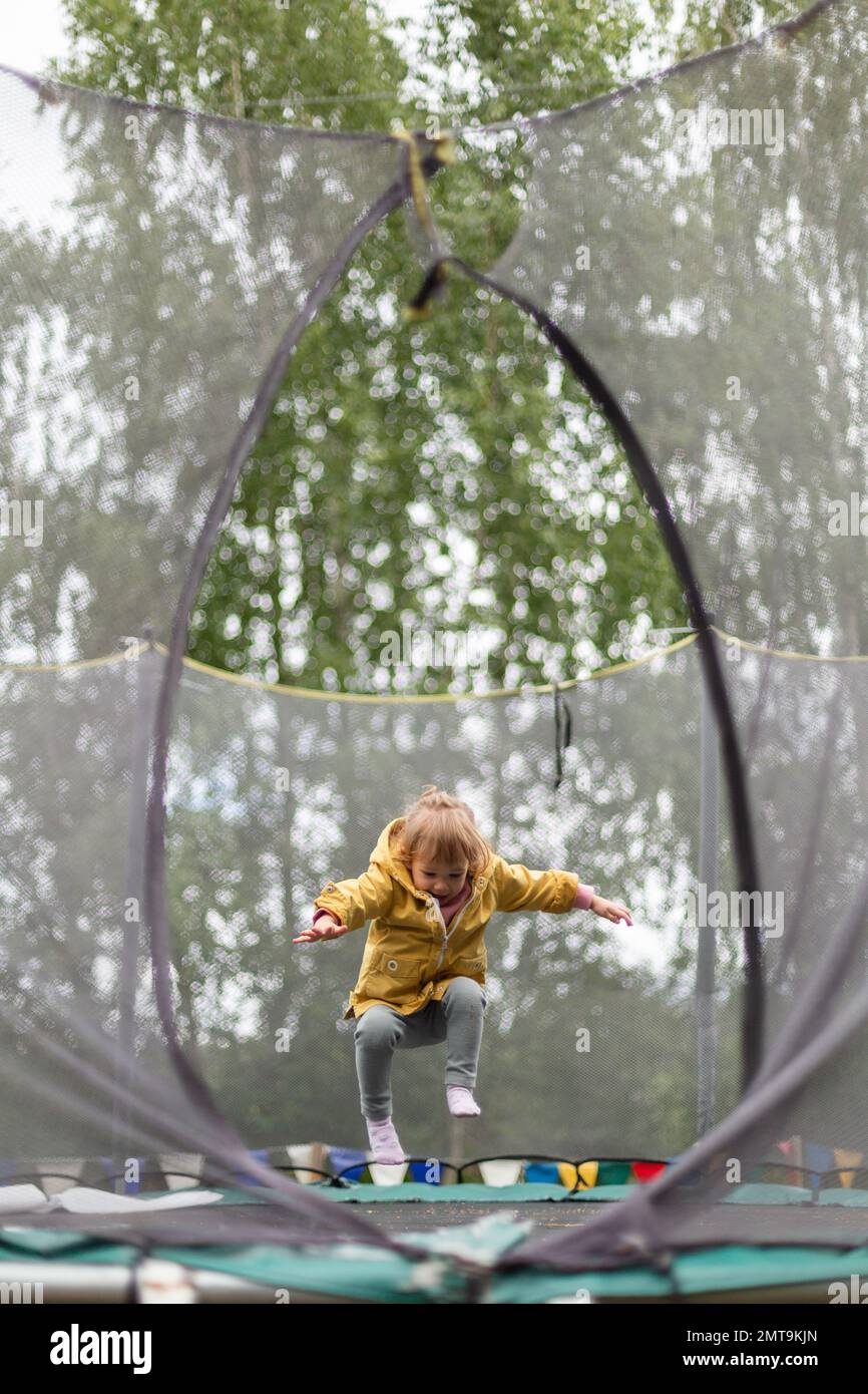 Little girl jumping on trampoline and going down the slide Stock Photo ...