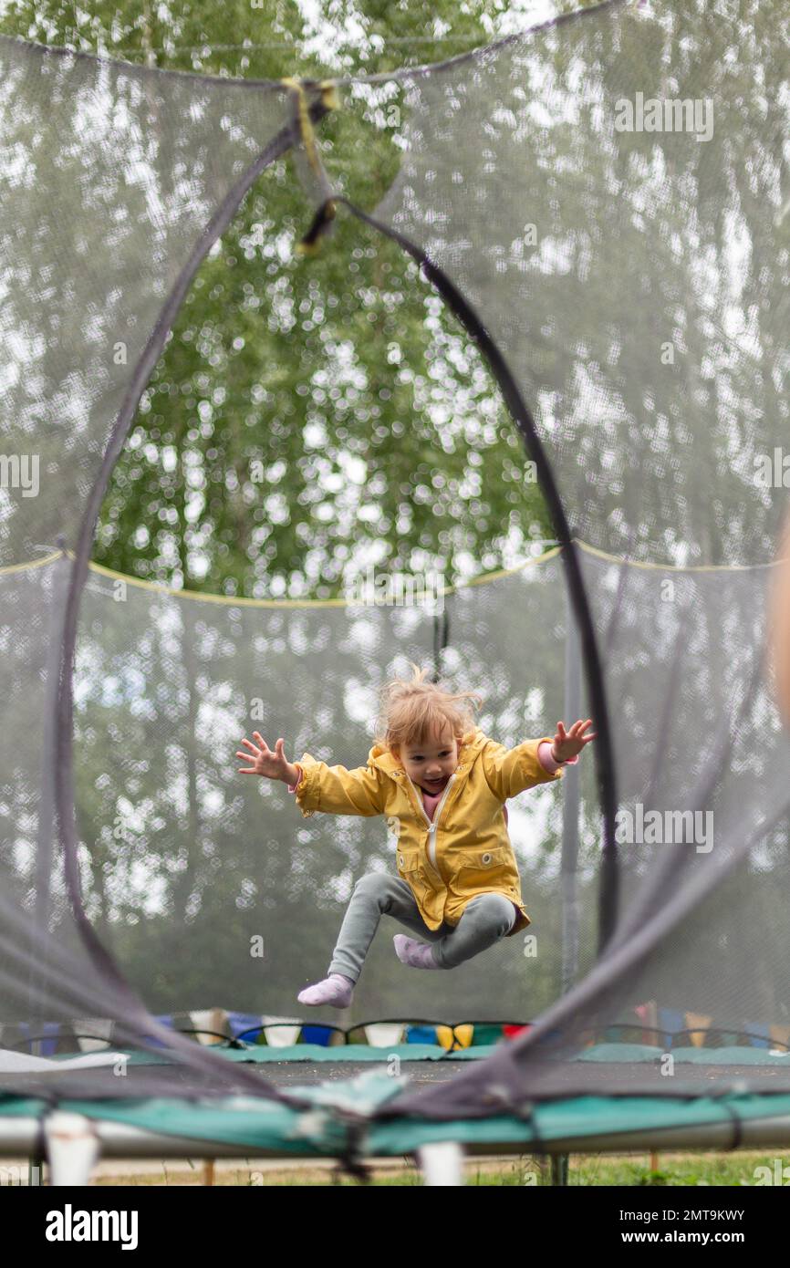 Little girl jumping on trampoline and going down the slide Stock Photo ...