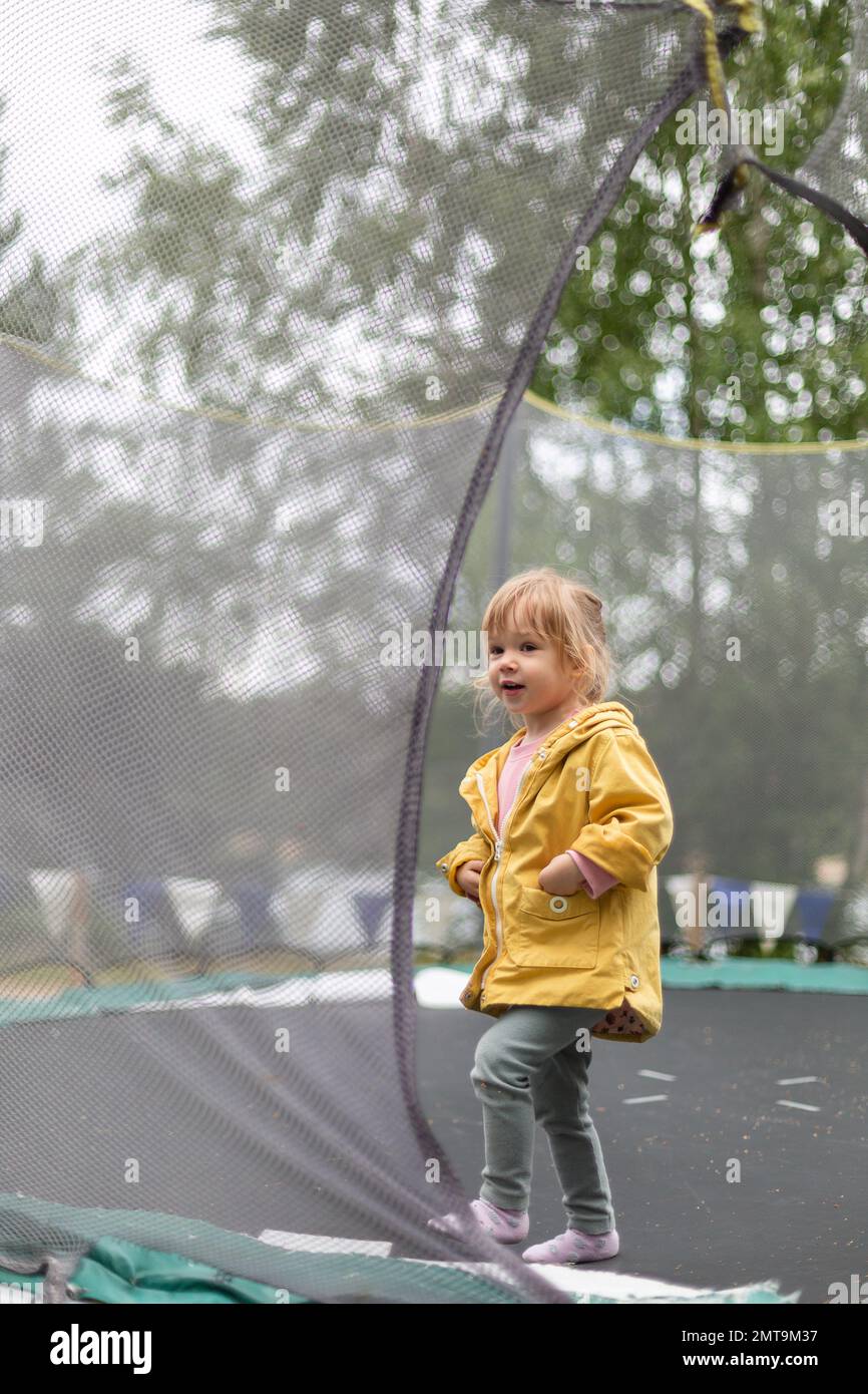 Little girl jumping on trampoline and going down the slide Stock Photo ...