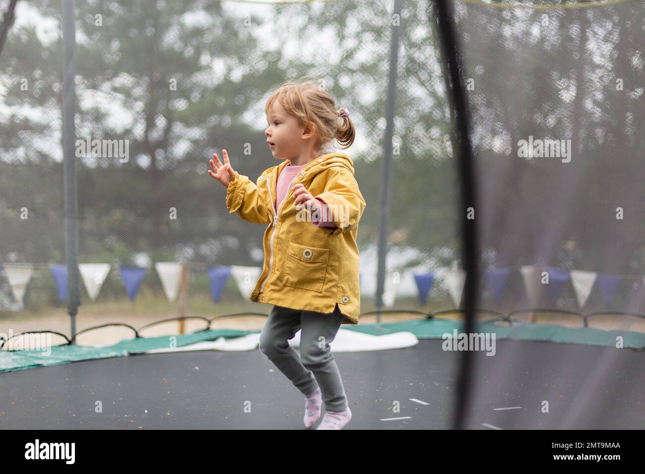 Little girl jumping on trampoline and going down the slide Stock Photo ...