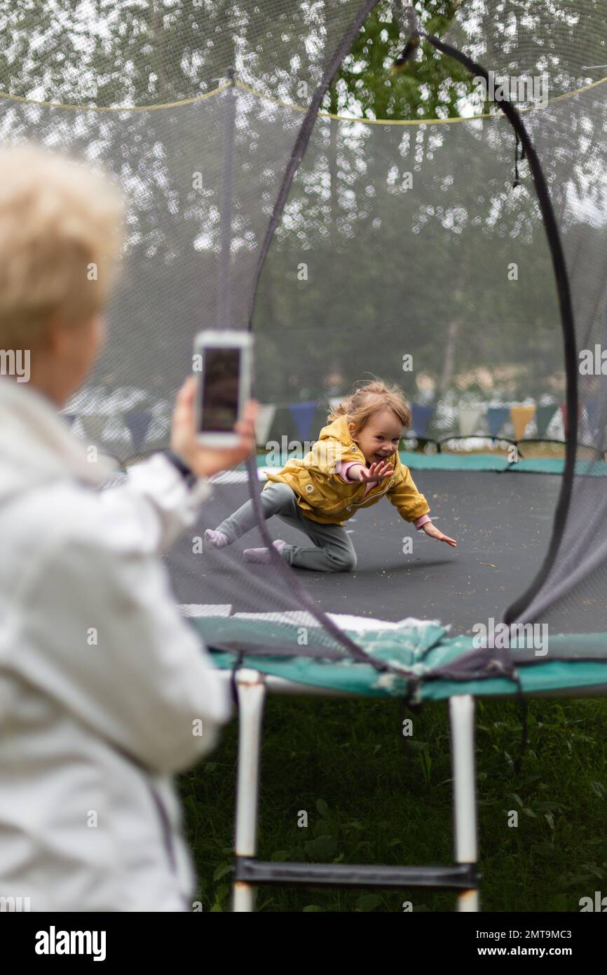Little girl jumping on trampoline and going down the slide Stock Photo ...