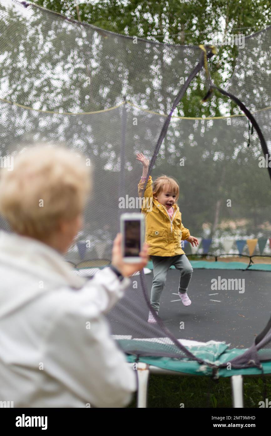 Little girl jumping on trampoline and going down the slide Stock Photo ...
