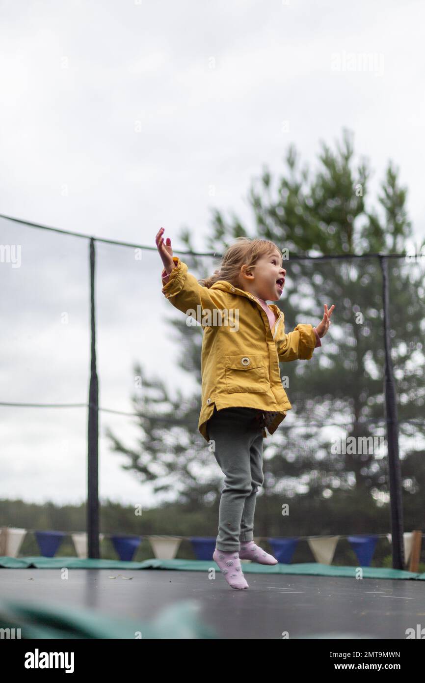 Little girl jumping on trampoline and going down the slide Stock Photo ...