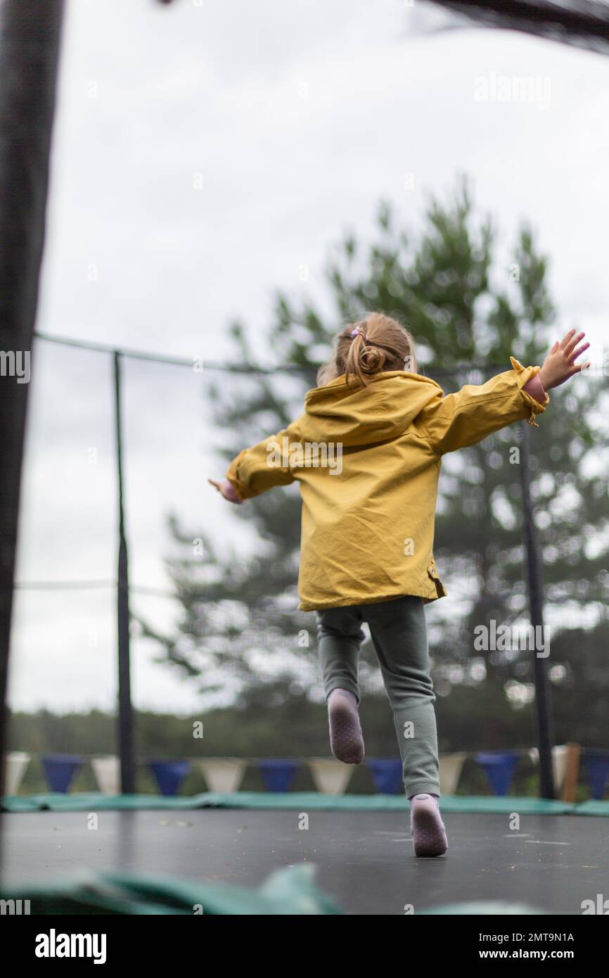 Little girl jumping on trampoline and going down the slide Stock Photo ...
