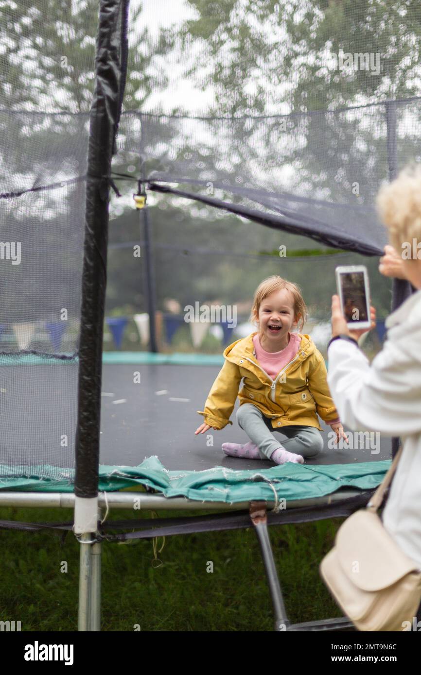 Little girl jumping on trampoline and going down the slide Stock Photo ...