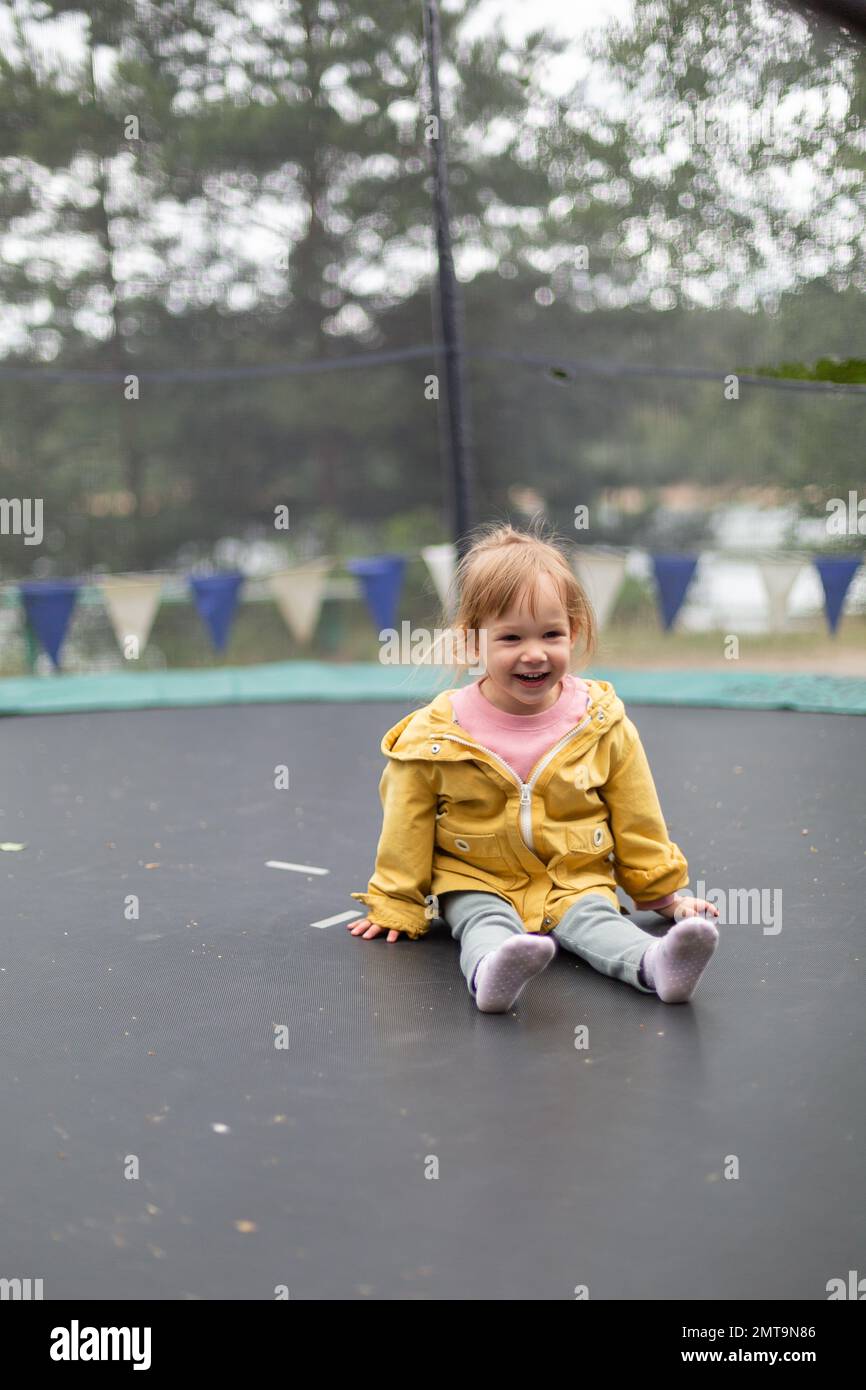 Little girl jumping on trampoline and going down the slide Stock Photo ...