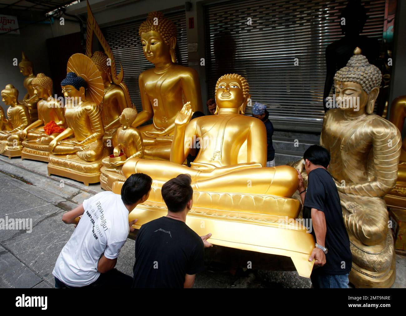 Thai workers remove Buddha statues at a shop in Bangkok, Thailand ...