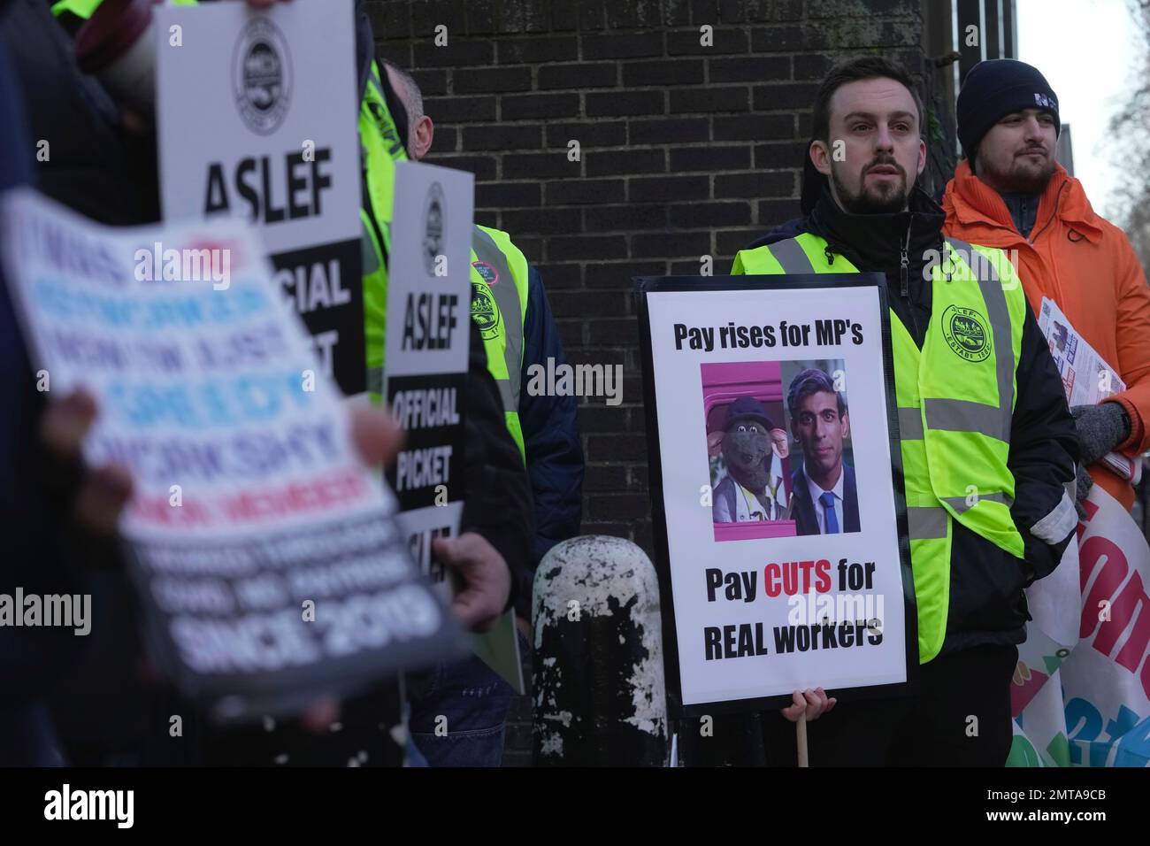 Rail workers hold up a sign with pictures of a television puppet ...