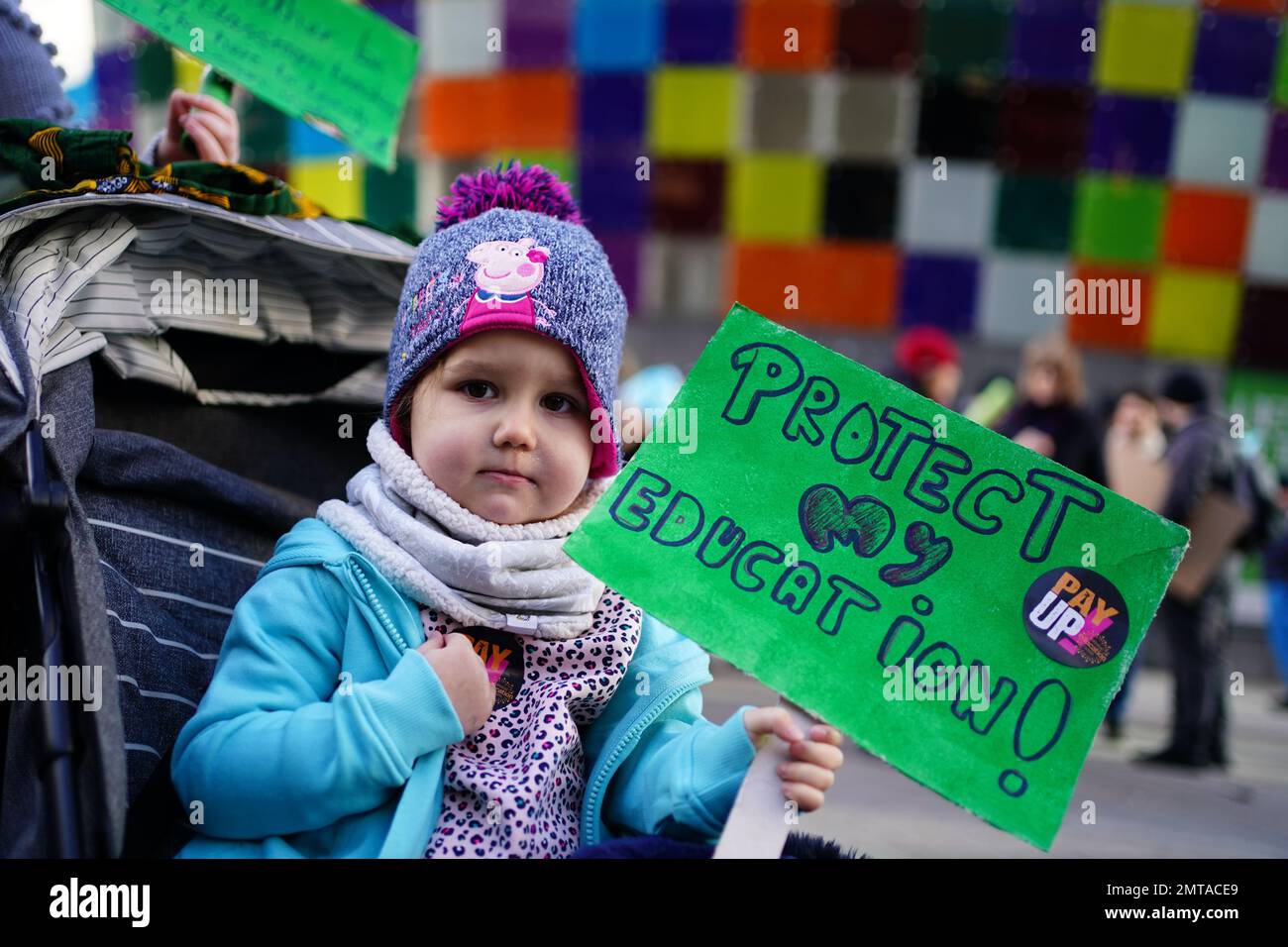 Nancy Moon, 2, holds up a placard as she joins strikers from across the ...