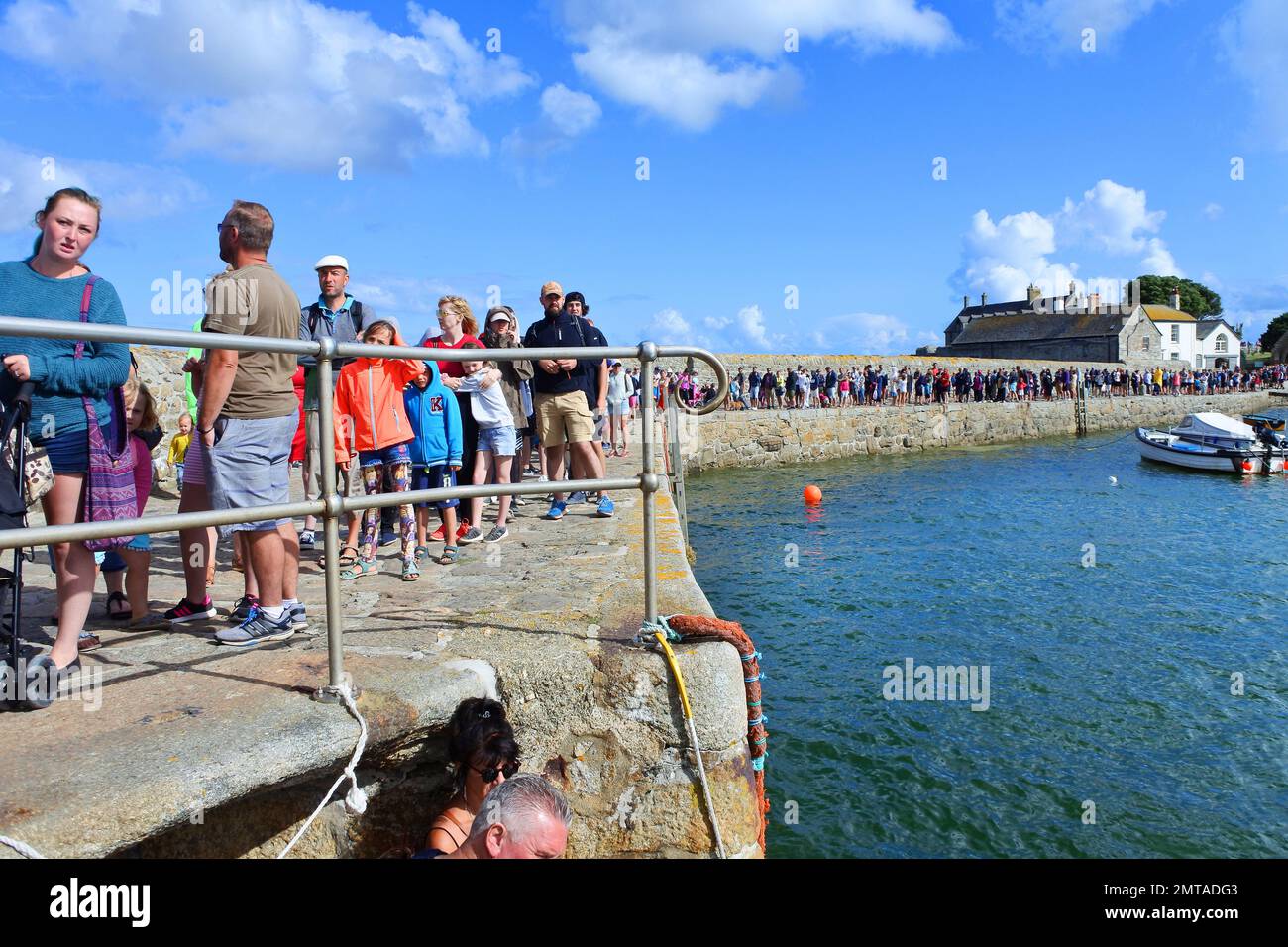 Long queue of tourists waiting to catch a ferry boat leaving St. Michael's Mount, Cornwall, UK ...