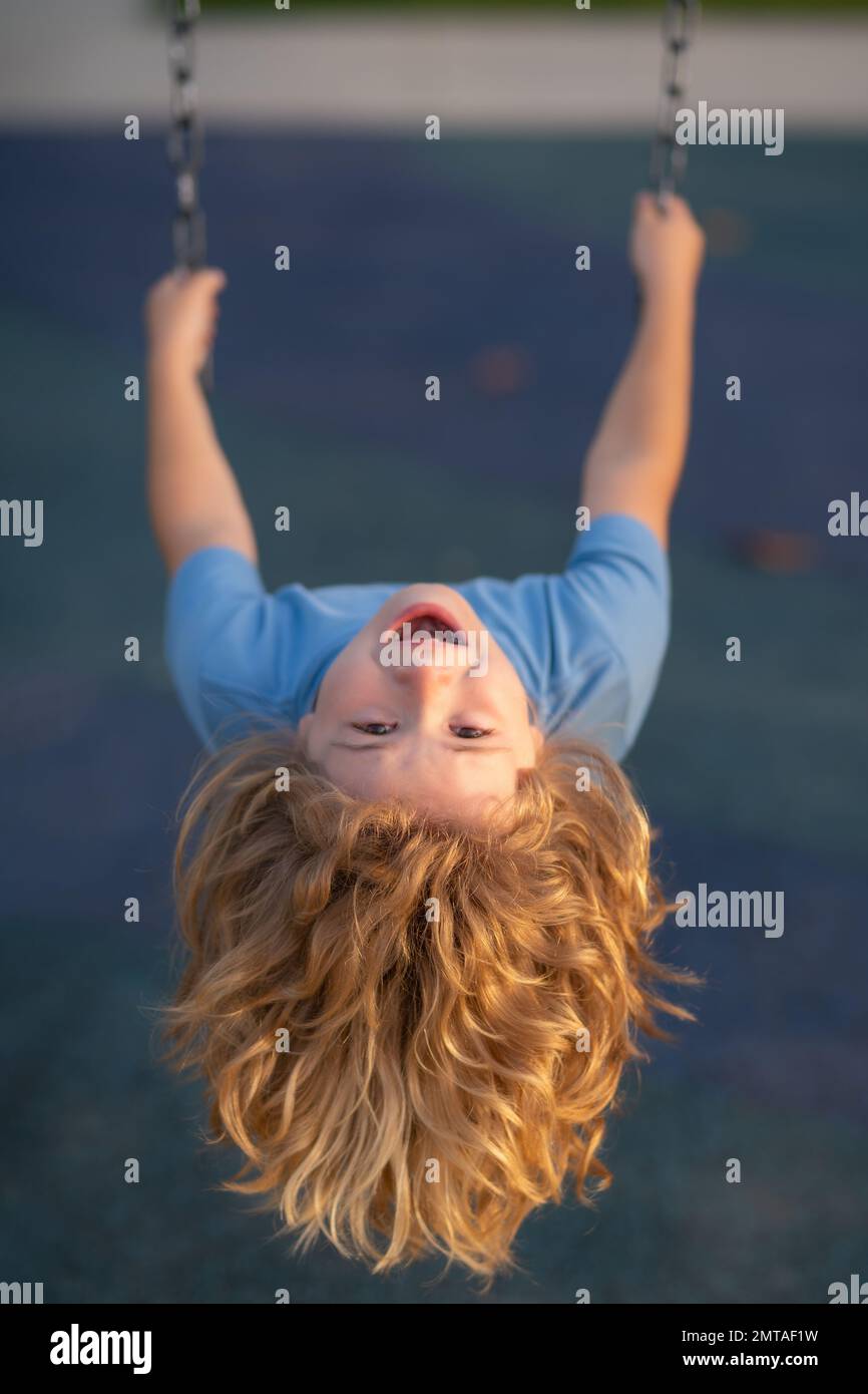 Funny child boy on swing. Kid swinging on playground. Cute excited amazed child on swing. Cute ...