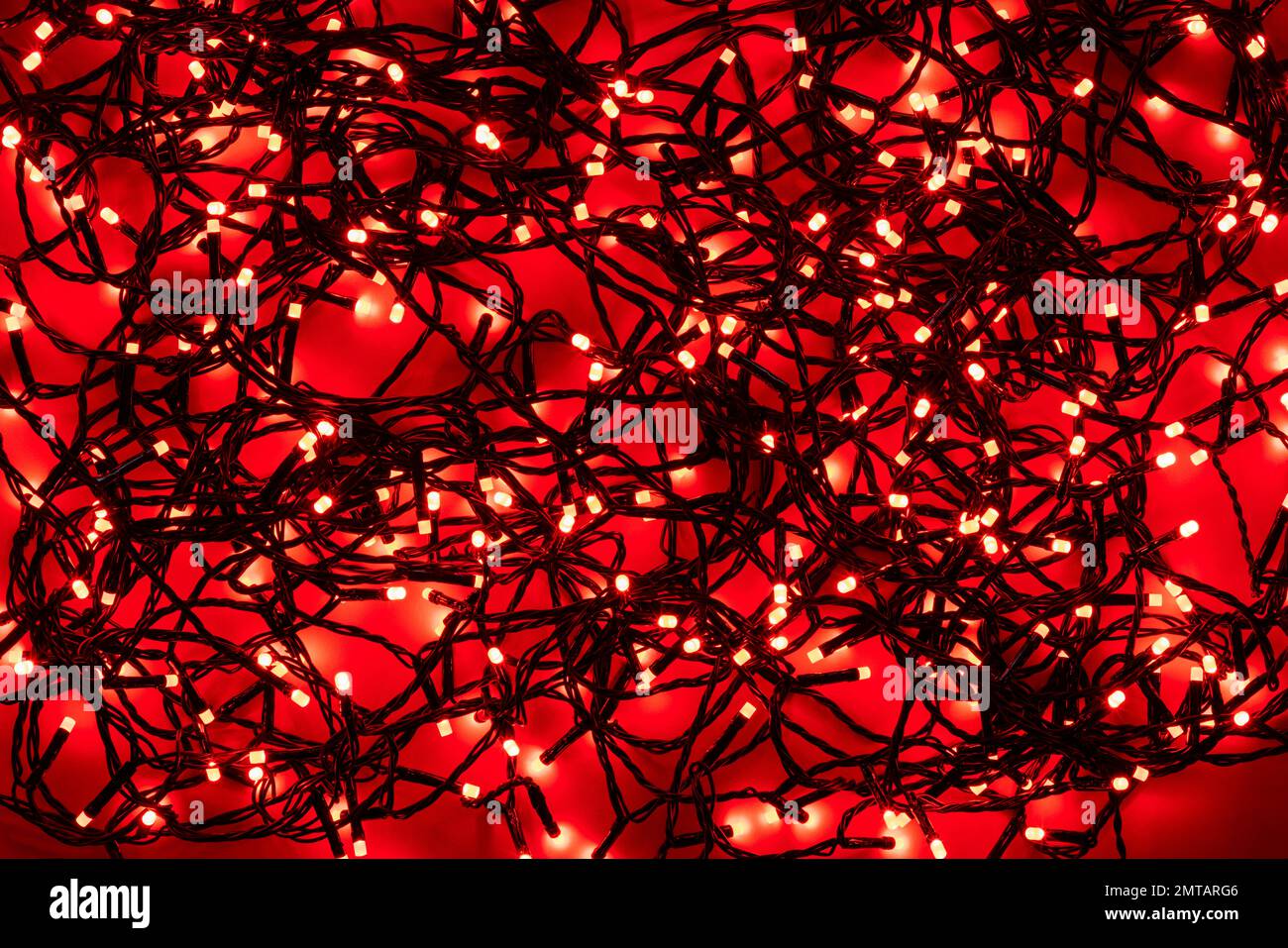 Tangled black wire garlands with red light bulbs on a red background ...