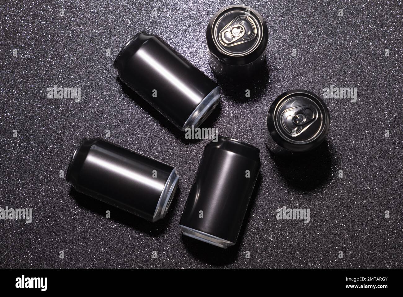 Five black aluminium soda cans on a black background with sparkles ...