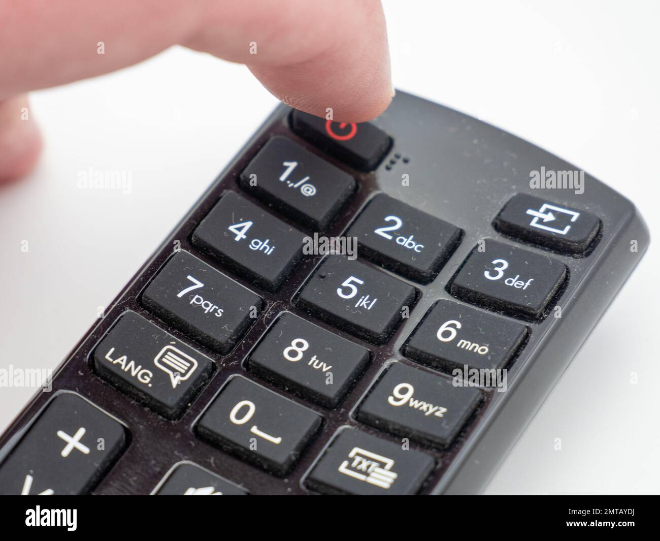 A black remote control isolated on a white background with a finger ...