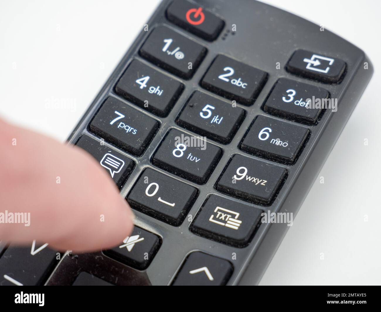 A black remote control isolated on a white background with a finger ...