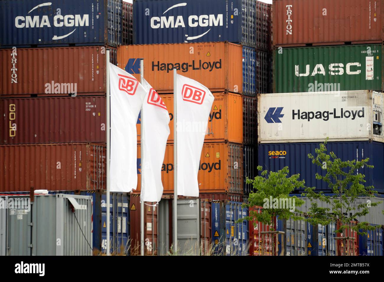 Shipping containers are stacked behind flags of German railway company ...