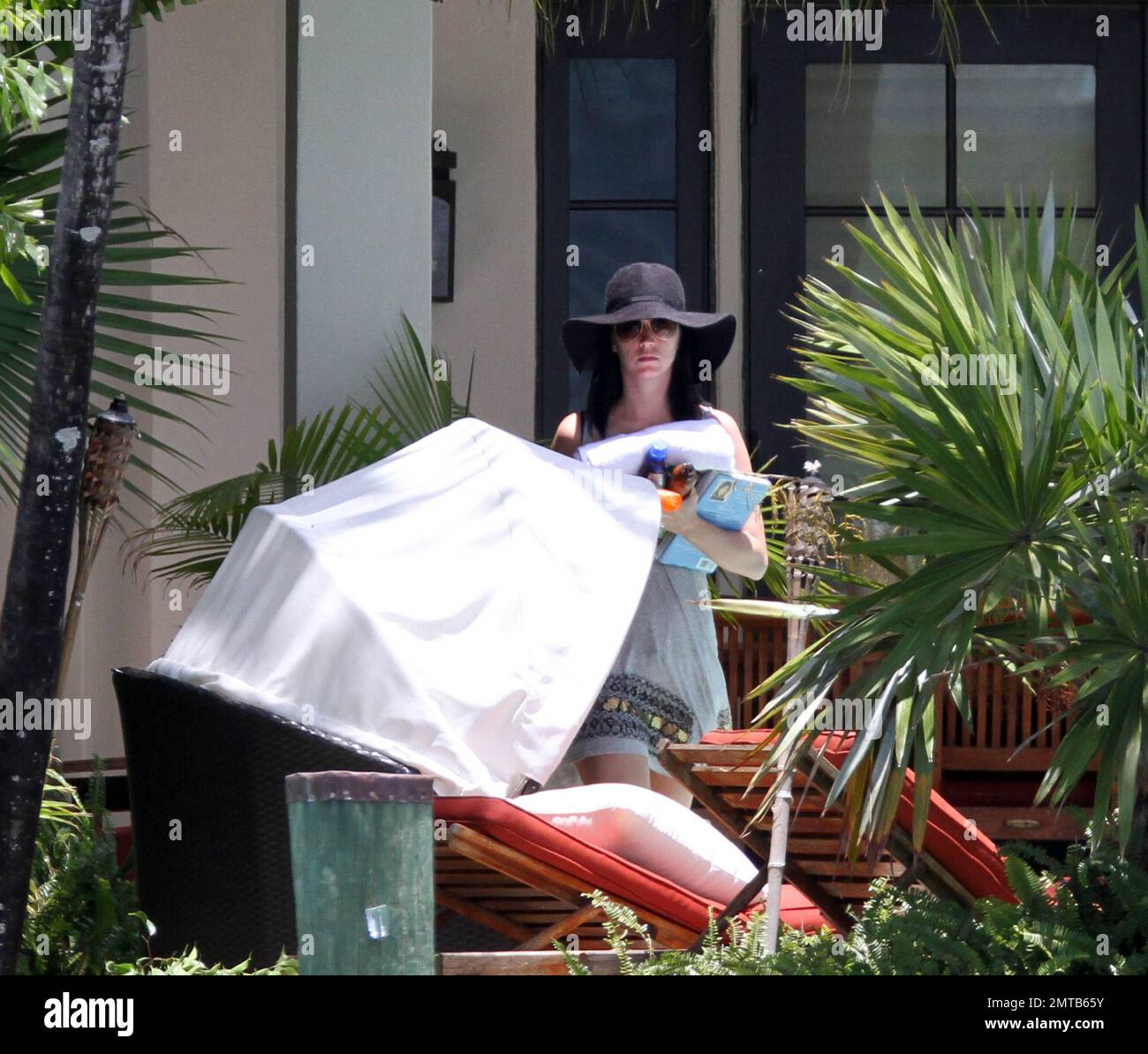 Katy Perry hides behind the trees in a pink polka dot bikini during a ...