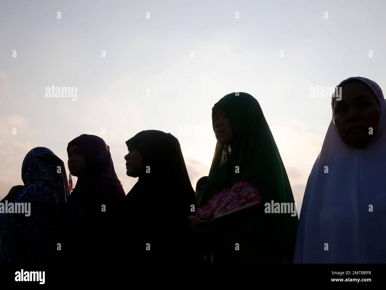 Filipino Muslims are silhouetted by the early morning sun as they at ...