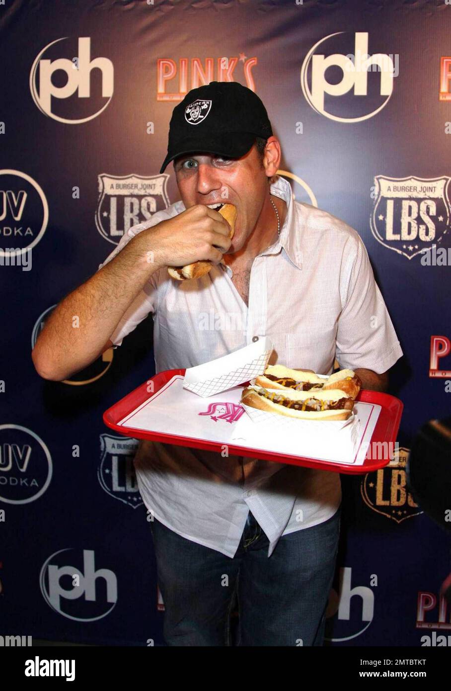 Owner Billy Pink poses on the pink carpet with a hot dog to celebrate ...