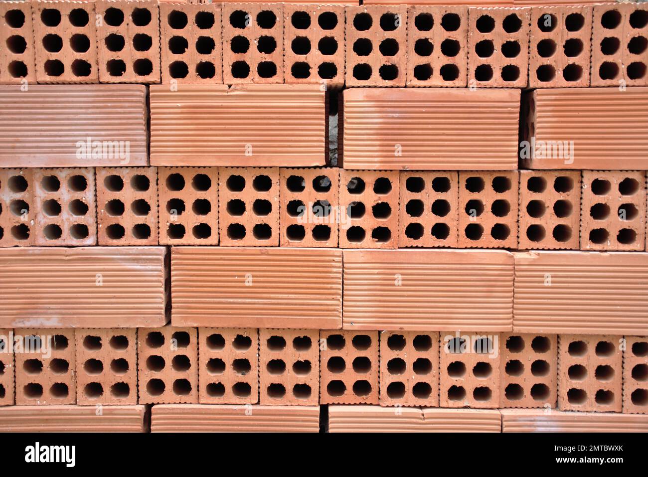 Background of baked clay bricks. Six-hole bricks stacked evenly ...