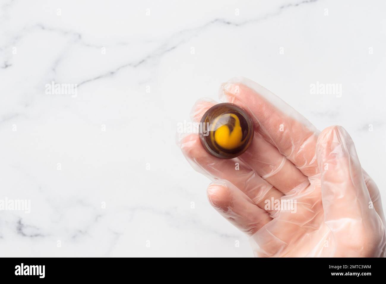 Painted handcrafted chocolate bonbon in a human hand. Delicious dessert ...