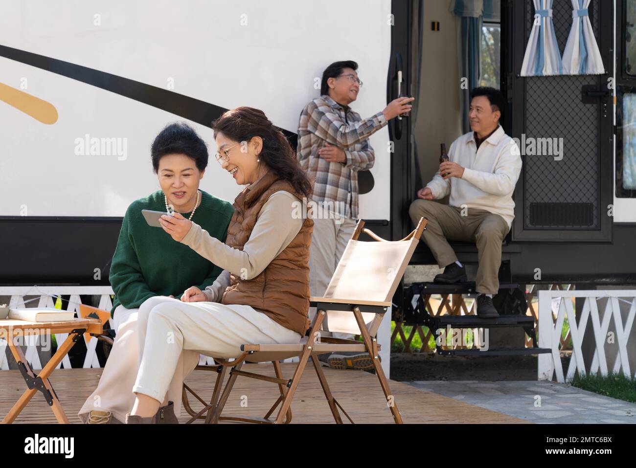 A group of old people sitting in the rv campsite beer watch video chat ...
