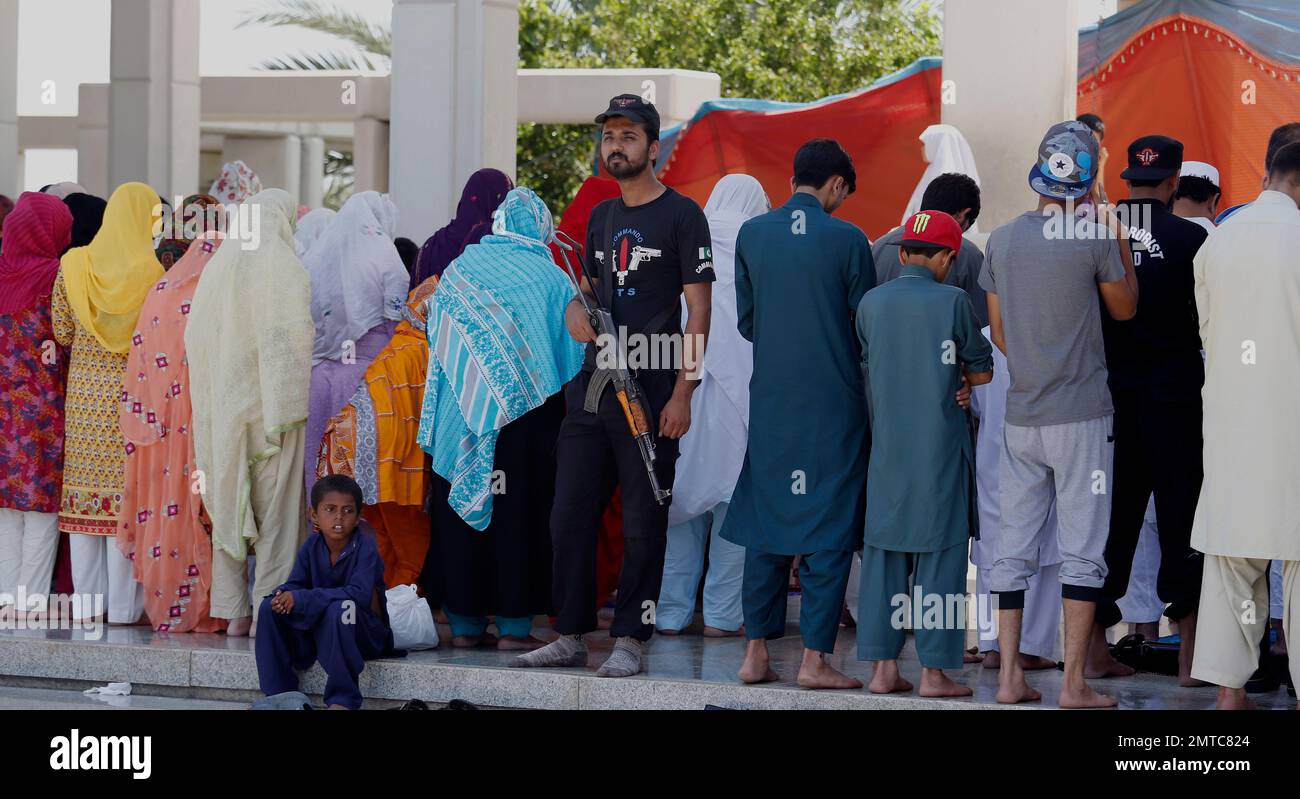 A Pakistani police commando stands alert while people offering prayer ...