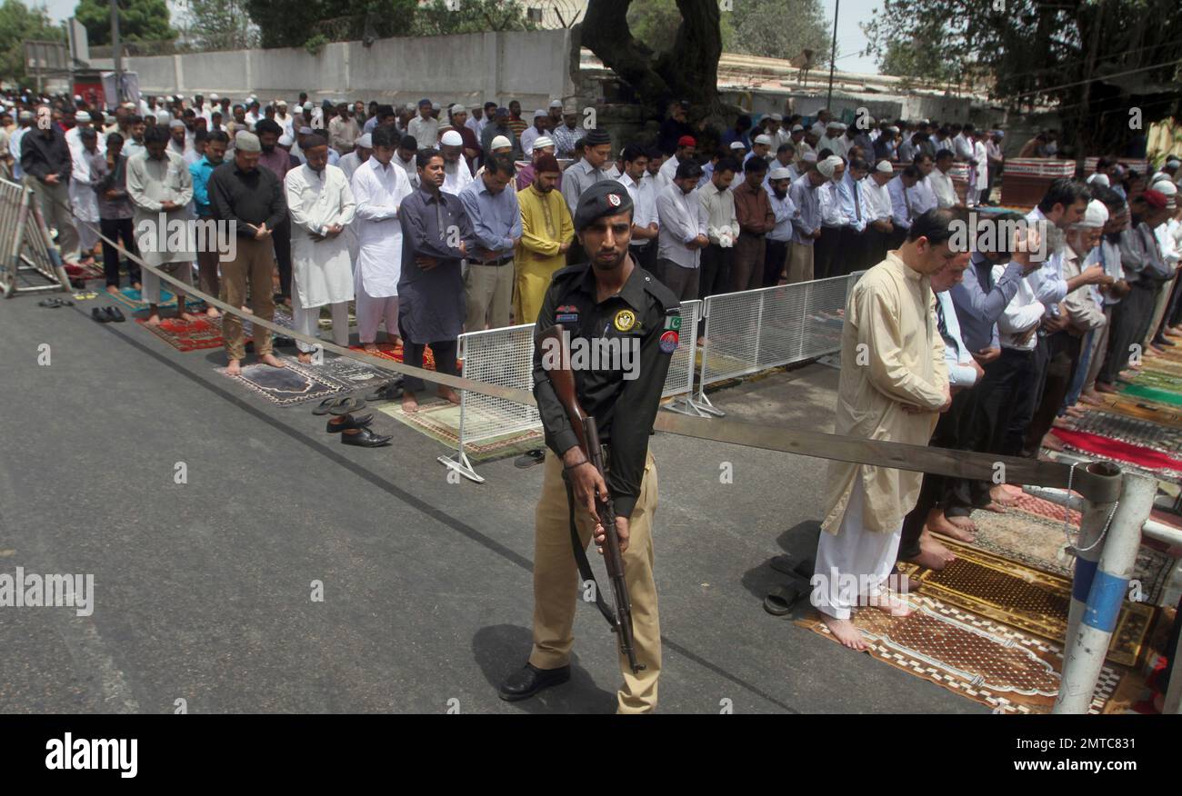 A Pakistani police officer stands guard while people offering prayer of ...