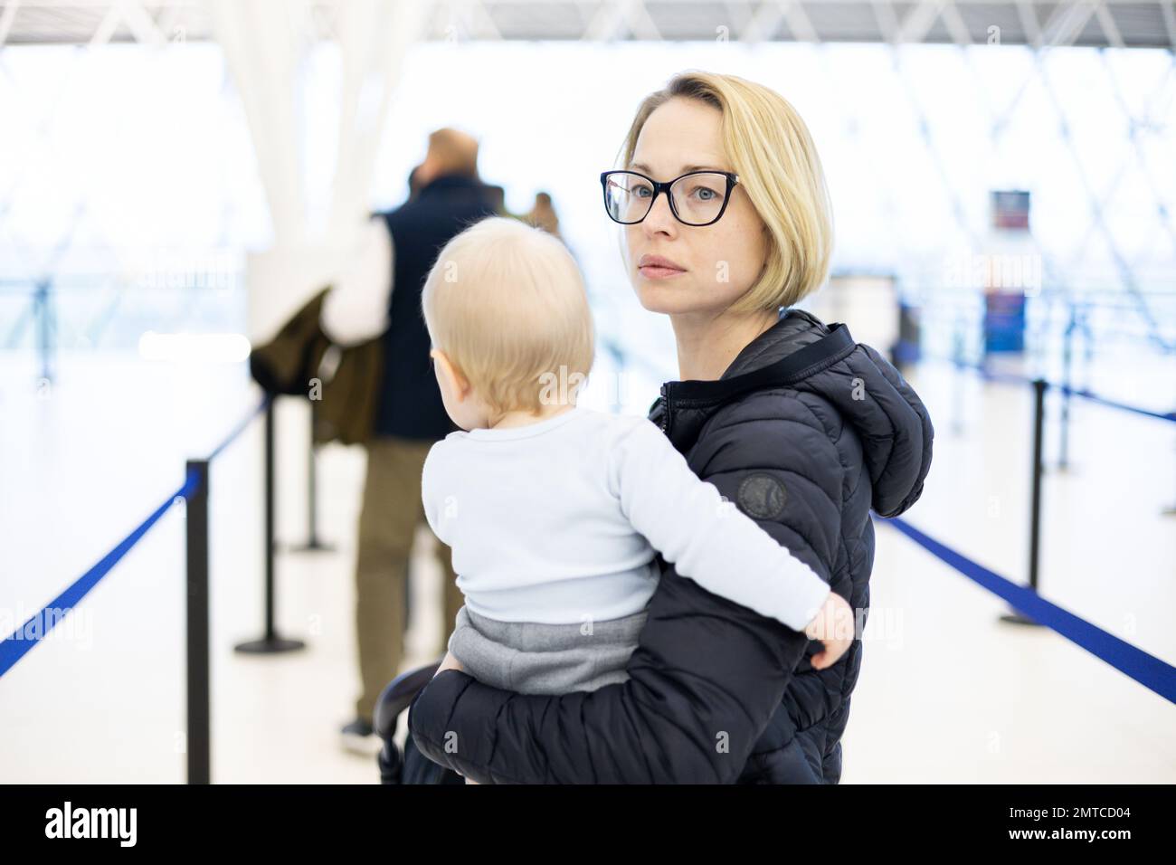 Mother holding his infant baby boy child queuing at airport terminal in ...