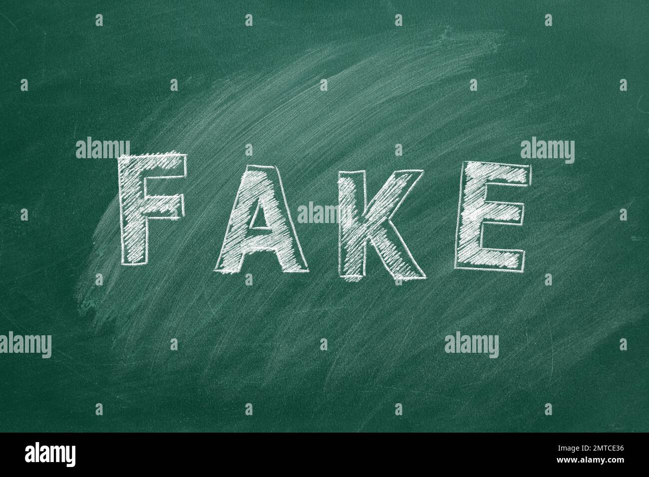 The word FAKE written in chalk on a greenboard. Information and ...