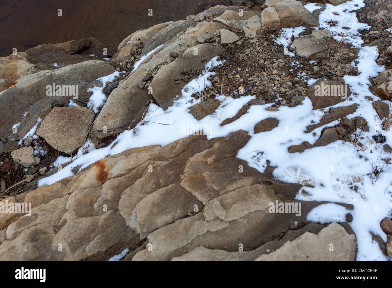 Stone rock rocks on the shore with clear water covered with snow Stock ...