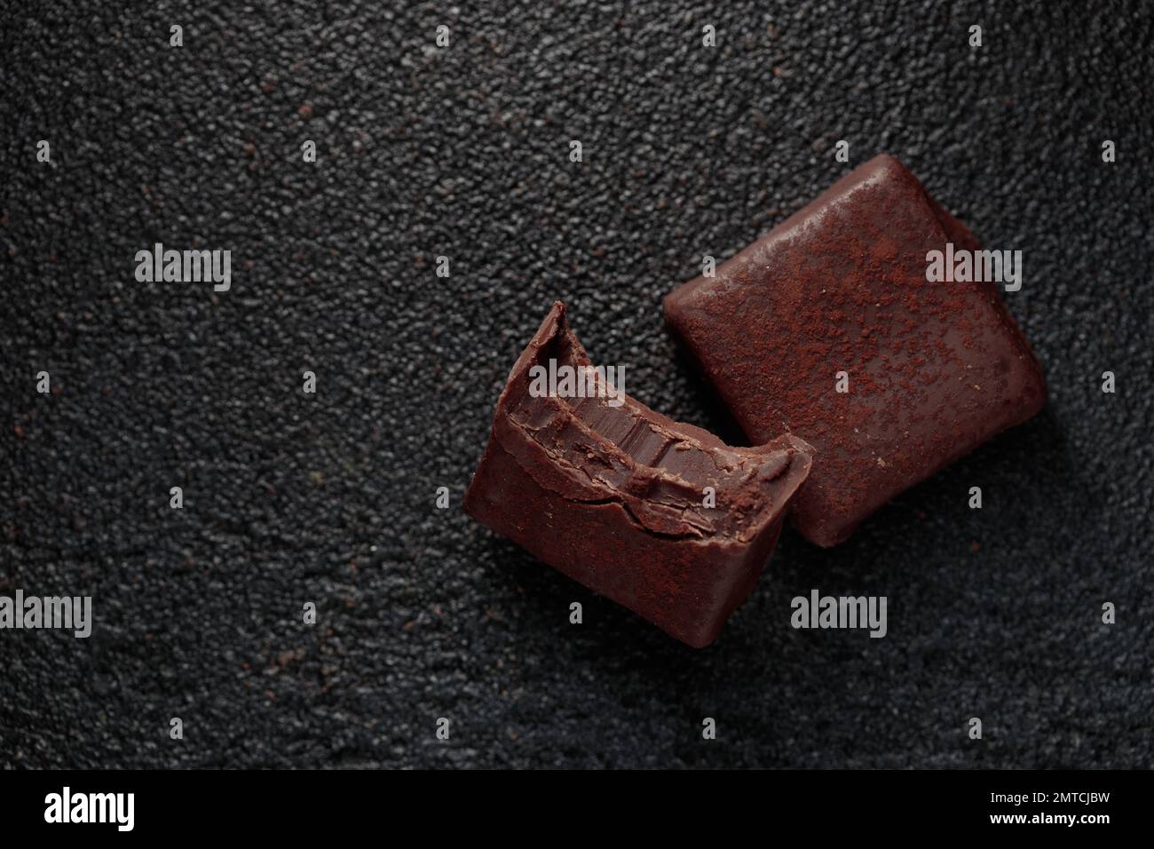 Chocolate handcrafted bonbons and bitten off piece of candy with ...