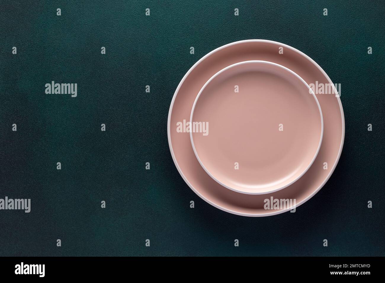Empty beige plates on a dark green table, grunge background. Top view ...