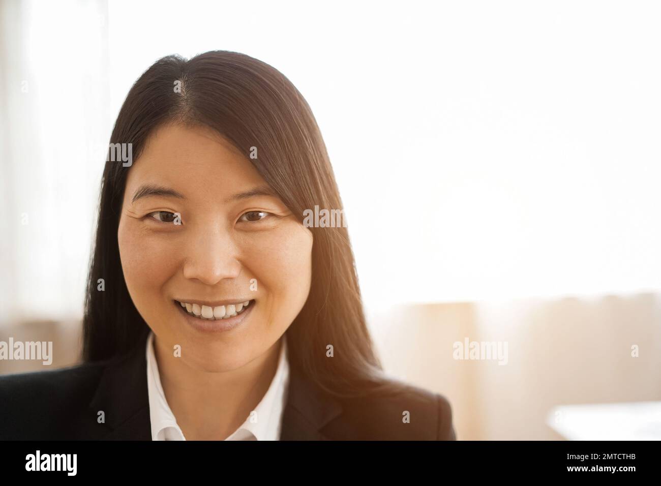 Asian young woman smiling on camera inside modern office - Focus on ...