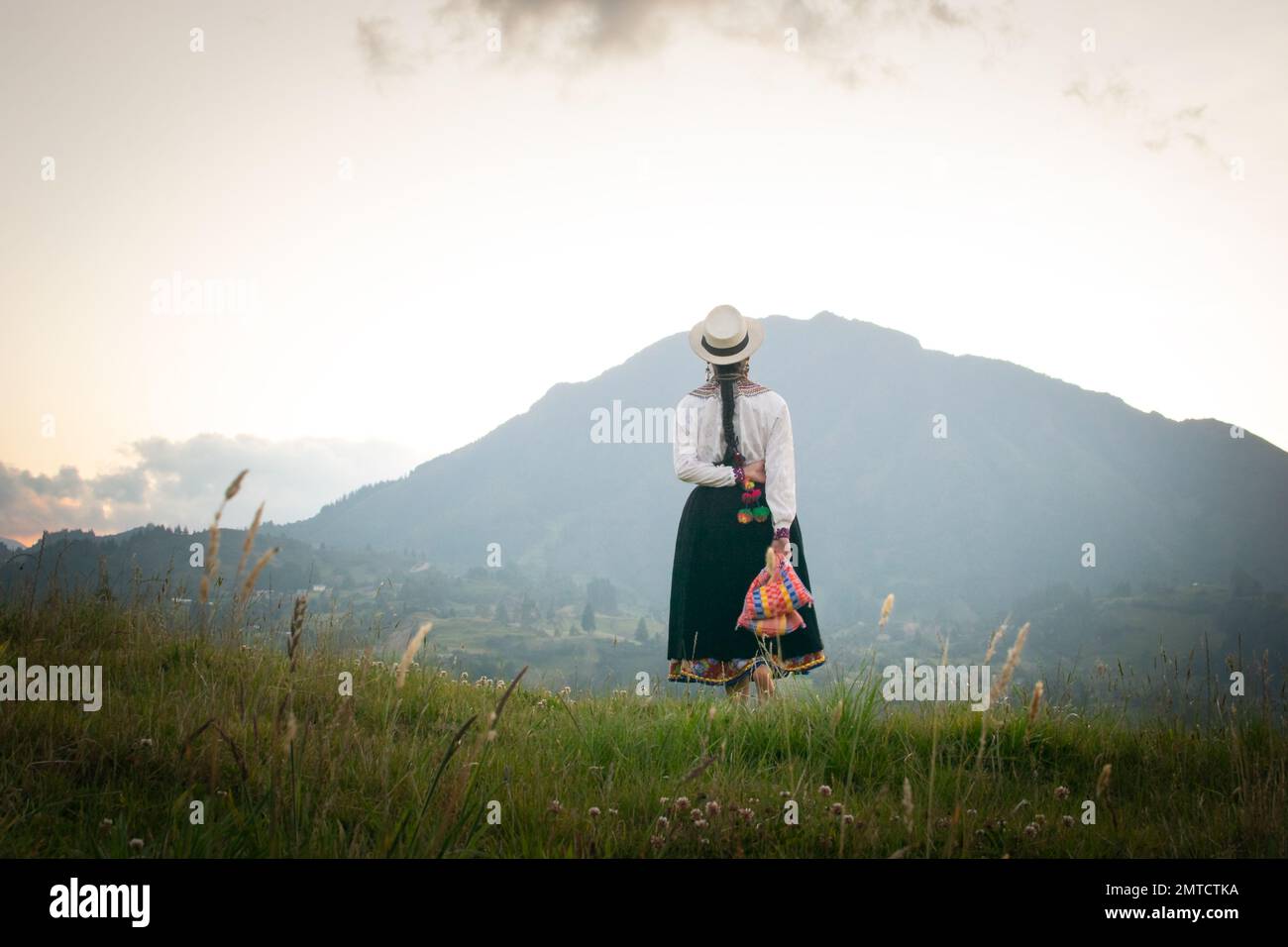 A back shot of Saraguro native girl walking wearing traditional regalia ...