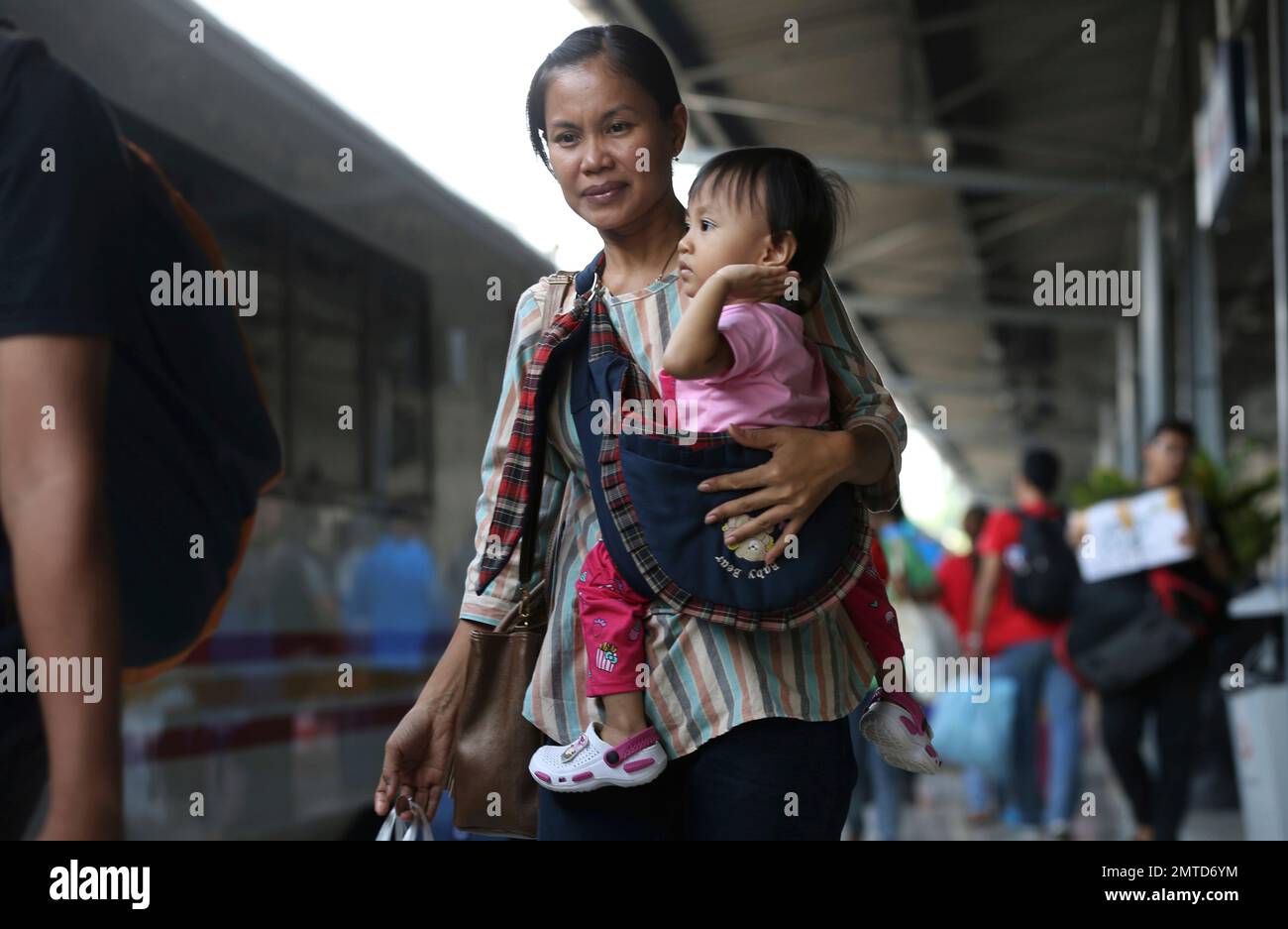 A woman carries her baby at Senen train station as they leave for their ...