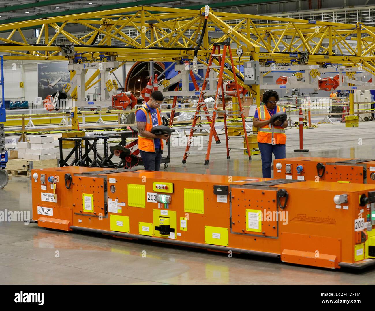 Workers test automated guided orange vehicles that will be used to move ...