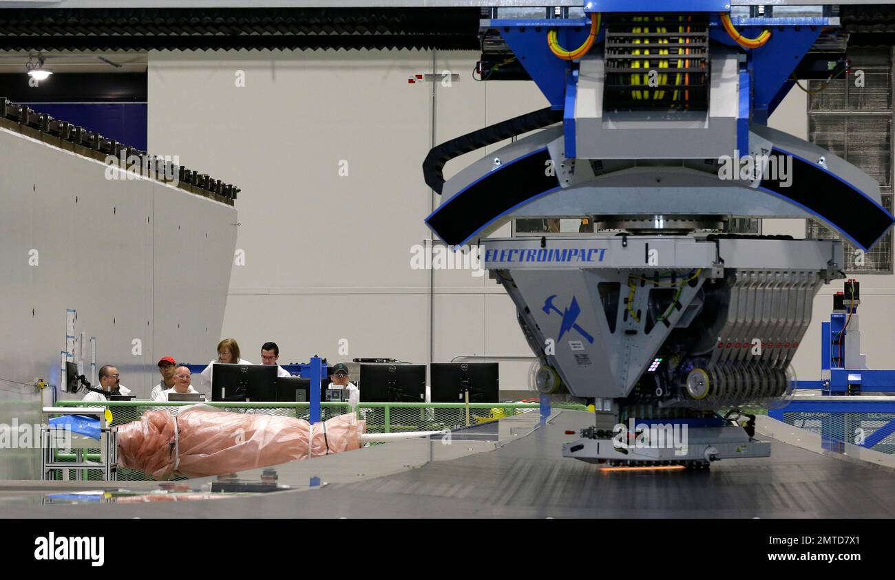 Workers operate a machine made by Electroimact Inc. that lays down ...