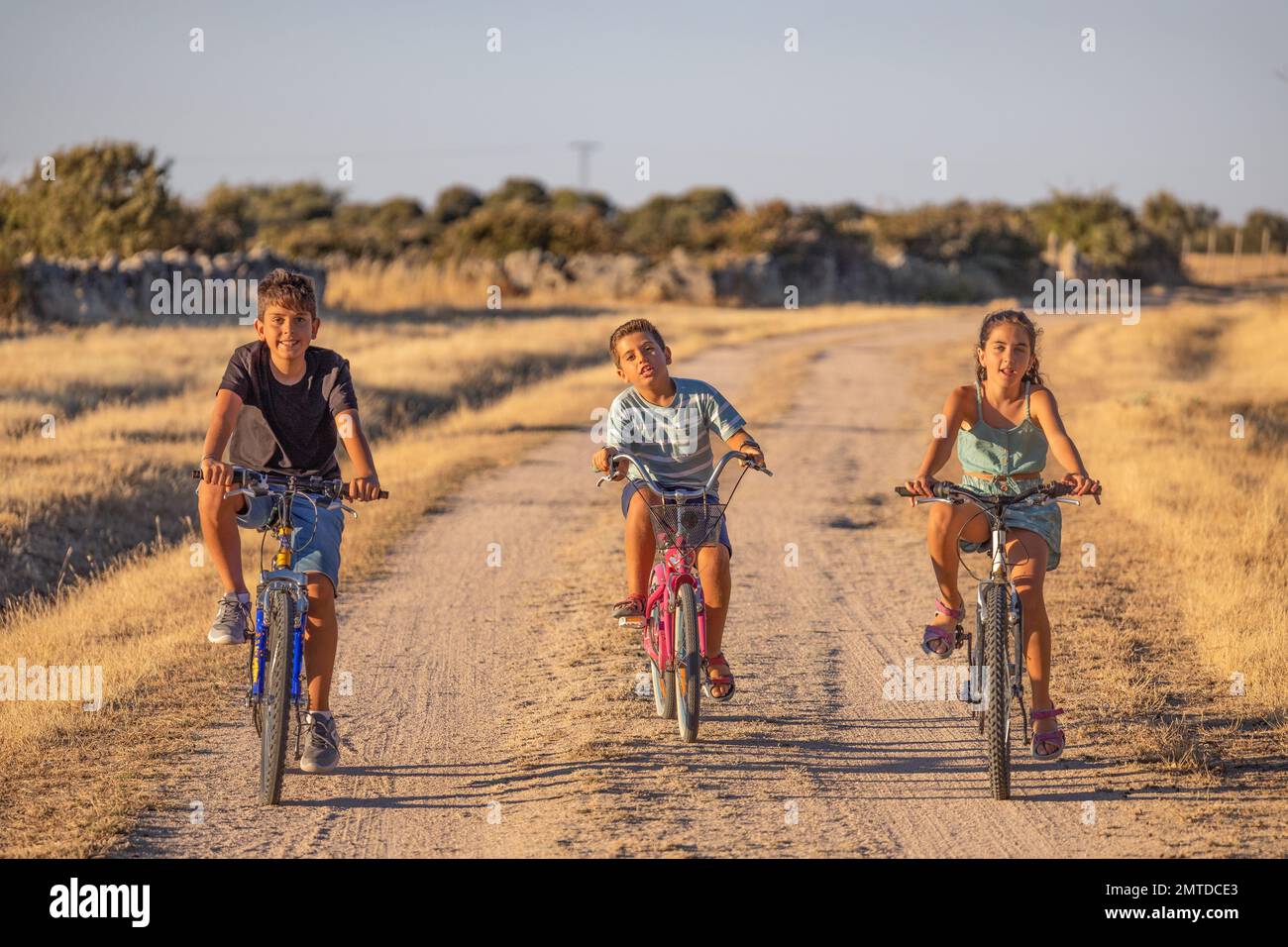 Three kids riding with theri bikes on a countryside Stock Photo - Alamy