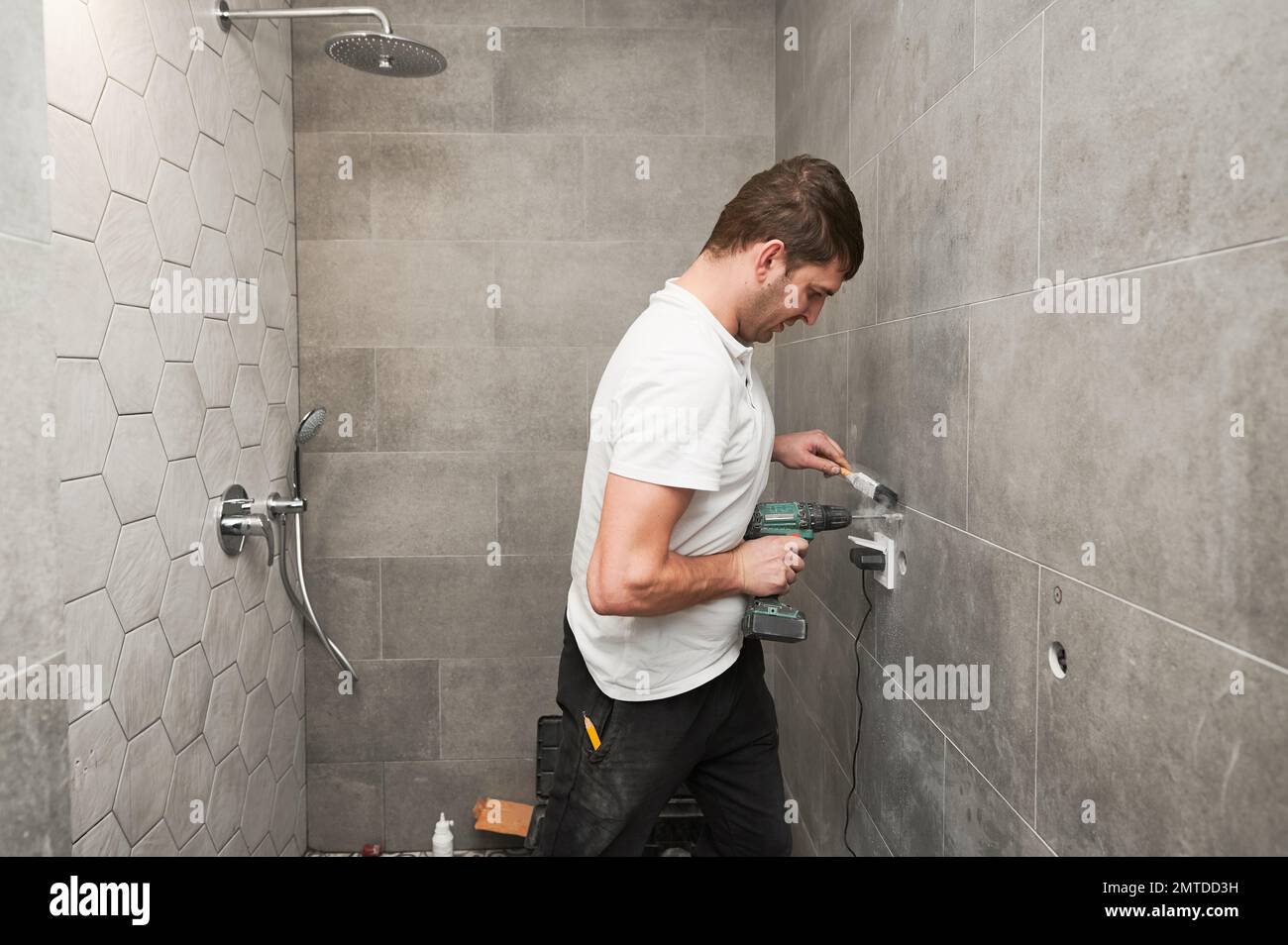 Side view of man using electric drilling machine and construction brush ...