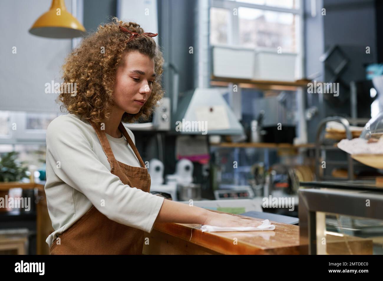 Young bakery worker cleaning counter before opening Stock Photo - Alamy