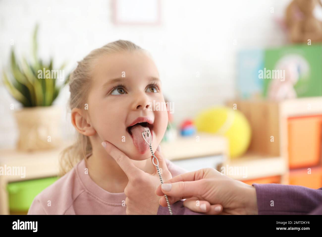 Speech therapist using logopedic probe on session with little girl in ...