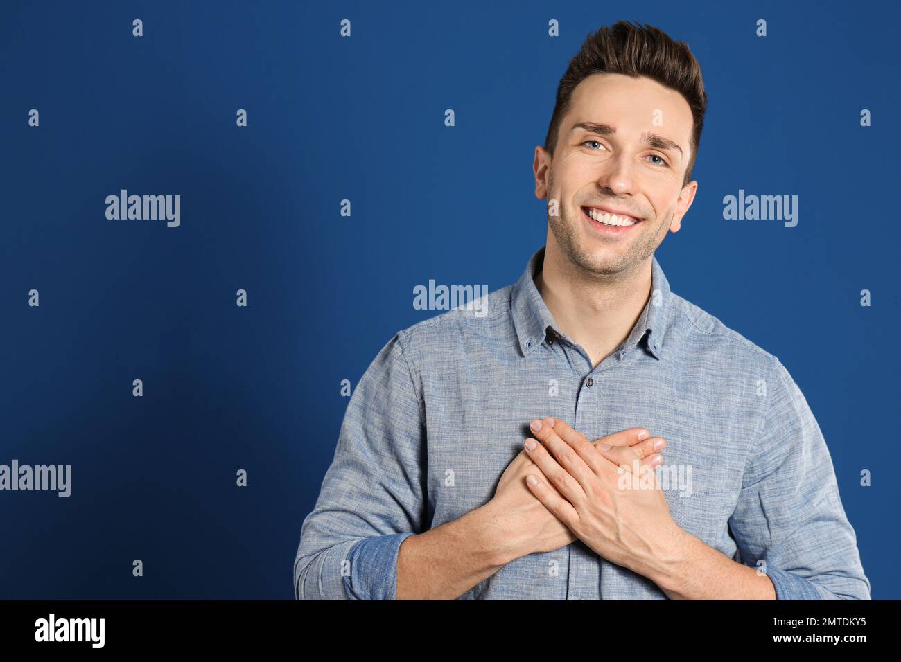 Handsome grateful man with hands on chest against blue background Stock ...