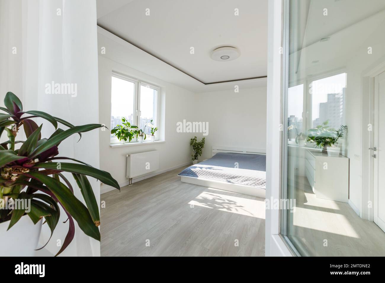 White bedroom with brick elements, balcony, double bed, desk Stock Photo - Alamy