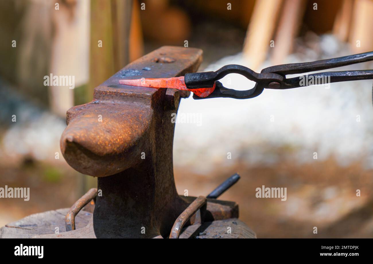 Blacksmith with red-hot iron at work Stock Photo - Alamy