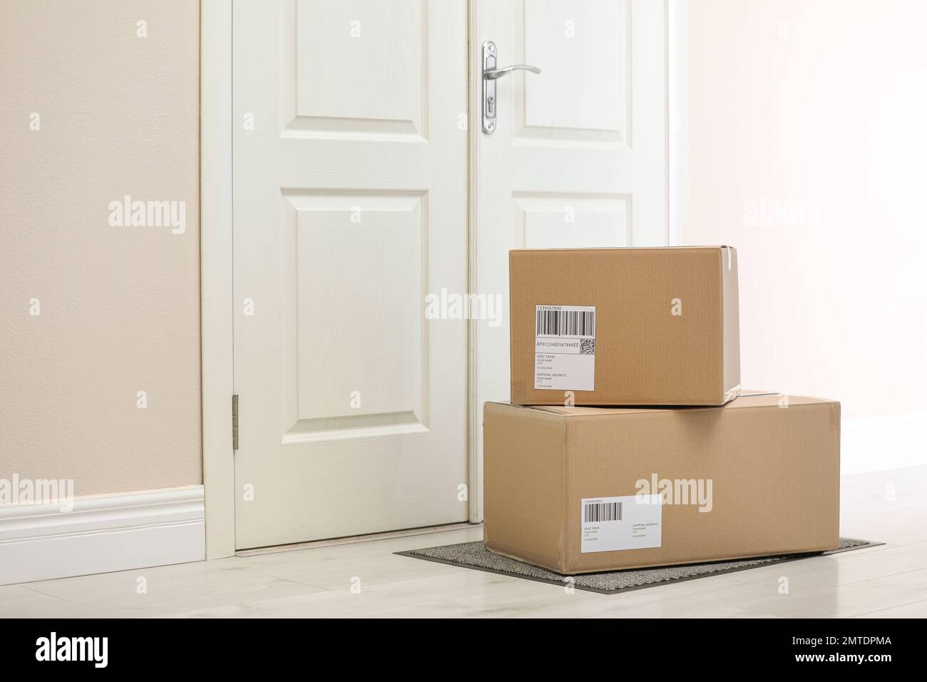 Parcels on rug near door. Delivery service Stock Photo - Alamy